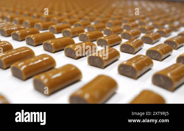 Chocolate candies in caramel move along a conveyor belt. Production of ...