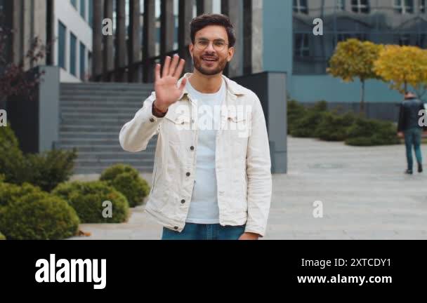 Hello. Indian man smiling friendly at camera, waving hands gesturing hi ...