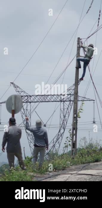three asian men work hard to install a new electrical cable in rural ...
