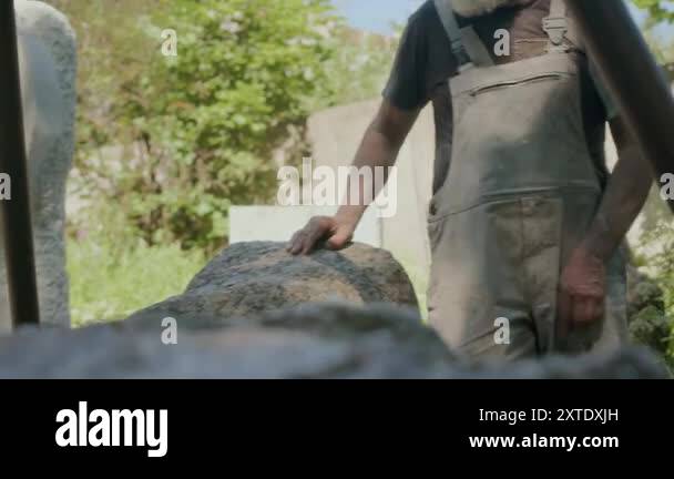 Medium shot of mature Caucasian male sculptor pulling chains while ...