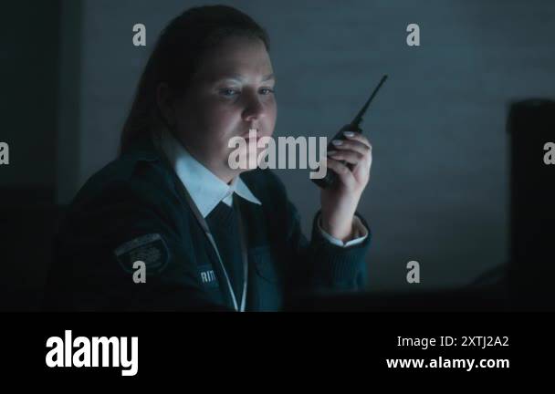 Female security officer or dispatch in uniform uses walkie talkie ...