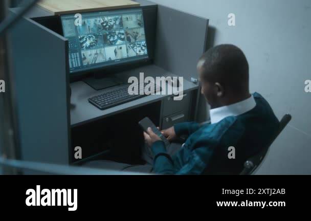African American male security guard sits at the workplace in the ...