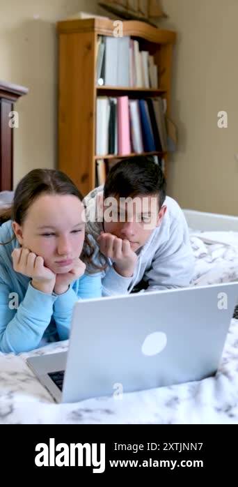 Toddler boy and schoolgirl watch online lesson on laptop sitting at ...