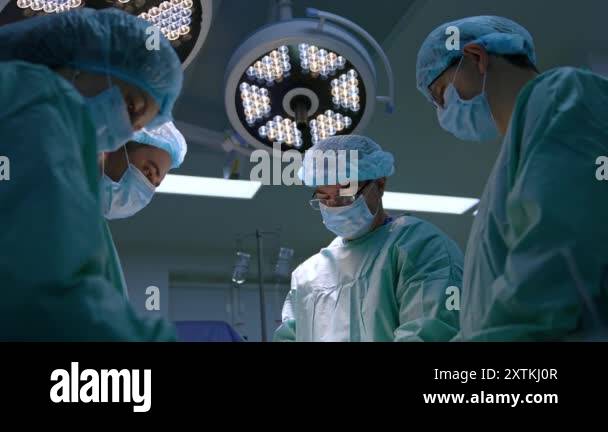 Four medics carrying out the operation in modern surgery rooms. Two big ...