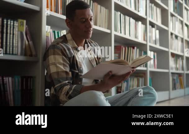 African American man sitting library floor bookcase reading book ...