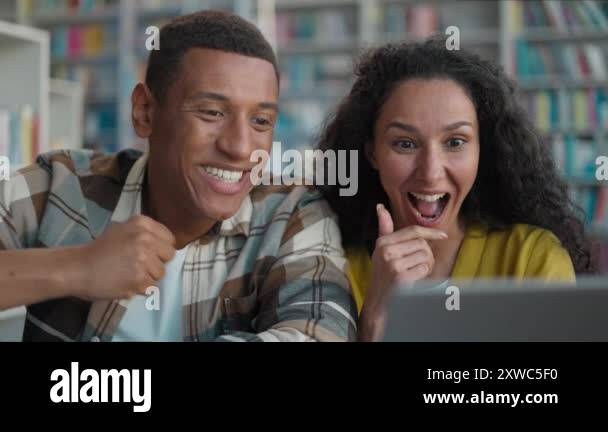 Happy African American man Arabian Latina woman using laptop computer technology device library ...