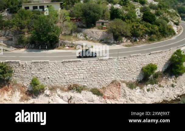 Auto with roof box drives along coastal road to lagoon with azure water ...