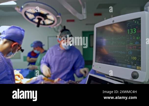 Monitor with life signs of a patient under surgery. Doctors' team work ...