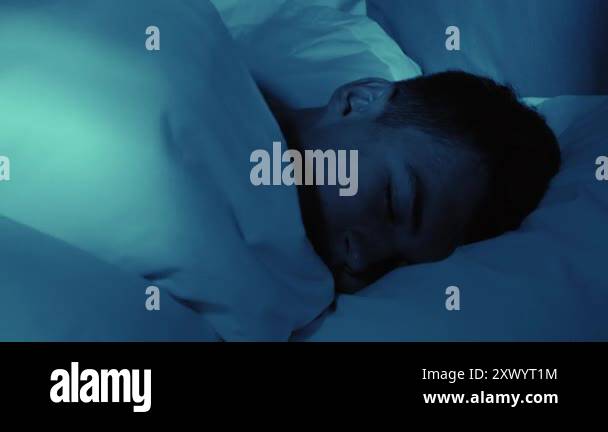 Disturbing sleep. Anxious man tossing turning under blanket in bed ...