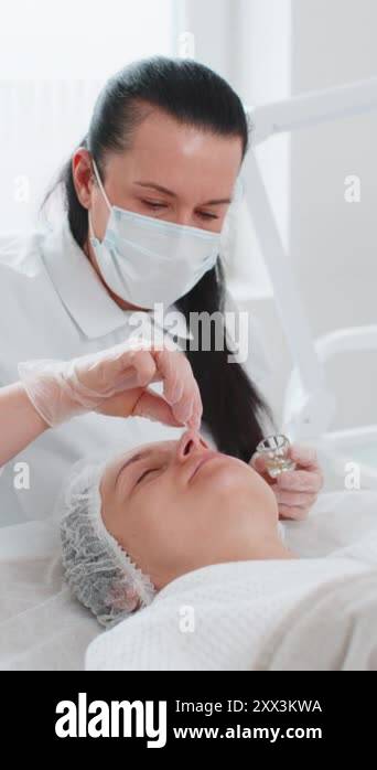 Beautician applying moisturizing acid cocktail peeling on woman face ...