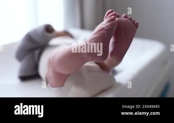 Newborn baby's wrinkled feet in focus while lying down, capturing the ...