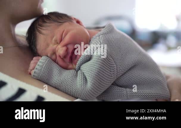 Newborn baby resting on mother's chest, visibly uncomfortable ...