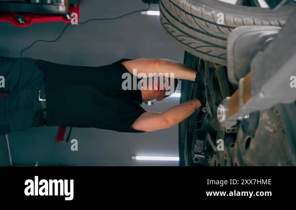 vertical video an auto mechanic at a service station checks a car being ...