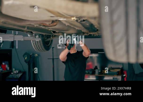 close up an auto mechanic at a service station checks a car being ...