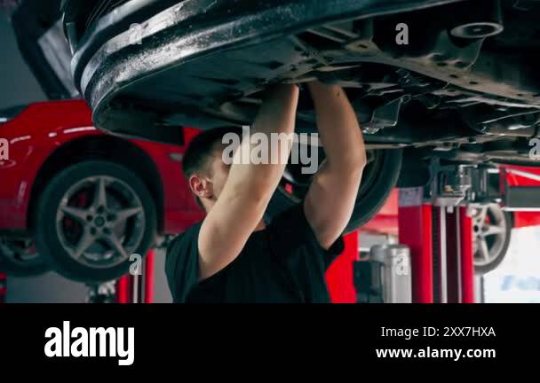 close up an auto mechanic at a service station checks a car being ...