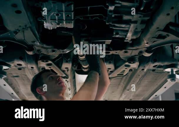close up an auto mechanic at a service station checks a car being ...