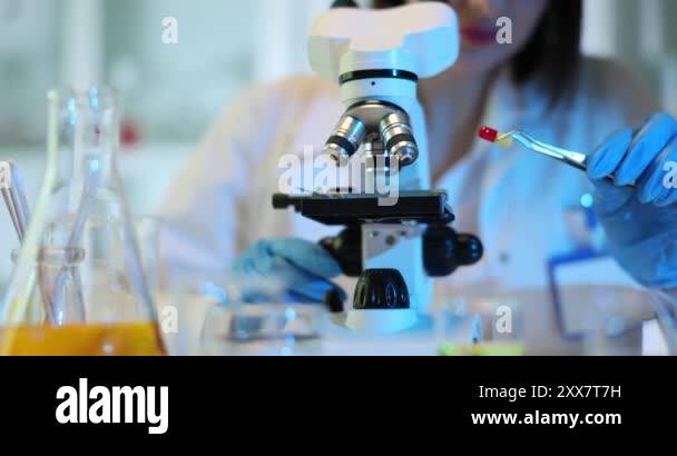 Scientist examining a sample of tablet under microscope in laboratory ...