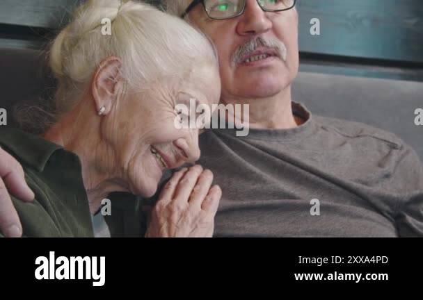 Close-up of faces of beautiful senior woman and man relaxing together at home on couch ...