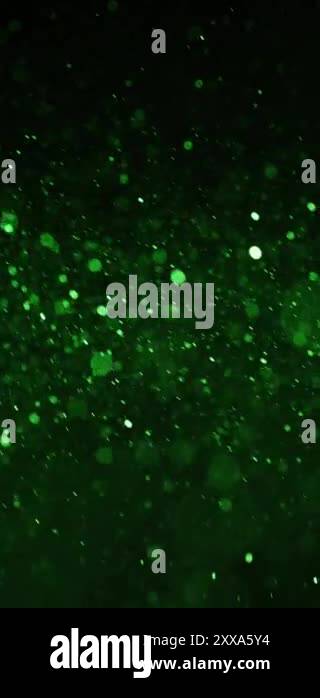 An array of green particles floats against a dark background. The ...