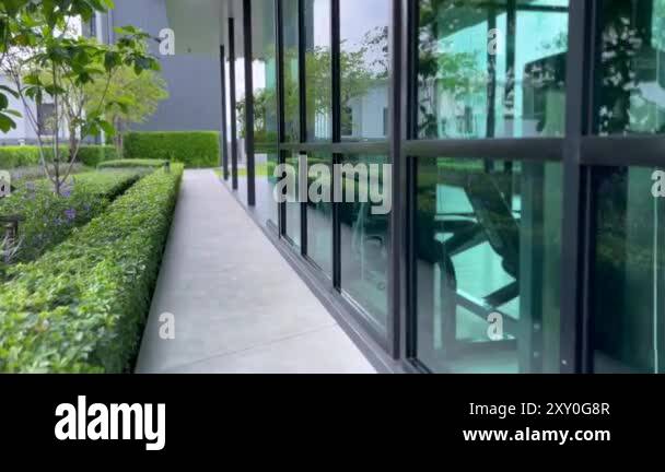 A modern outdoor garden walkway adjacent to a glass walled gym ...