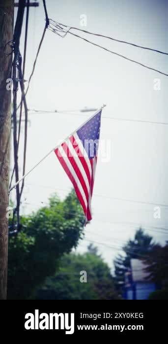The flag of the U.S. waves proudly from a wooden utility pole, set ...