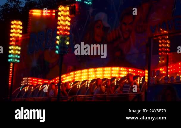 A vibrant amusement ride adorned with glowing lights against the night ...