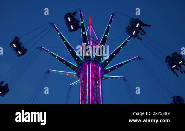 A vibrant amusement ride adorned with glowing lights against the night ...