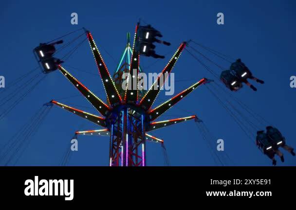 A vibrant amusement ride adorned with glowing lights against the night ...