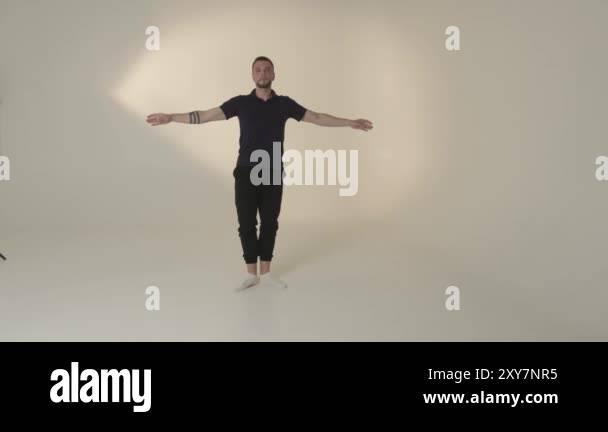 A person displays a dynamic dance pose in a minimalist studio that ...