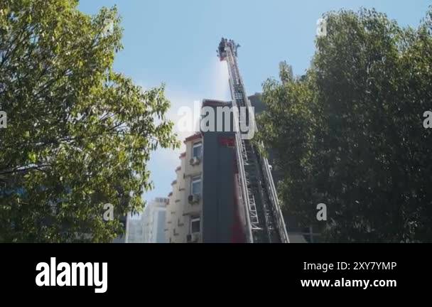 Back view of firefighters in elevated platform extinguish burning house ...