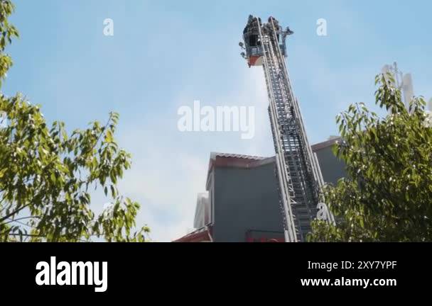 Back view of firefighters in elevated platform extinguish burning house ...