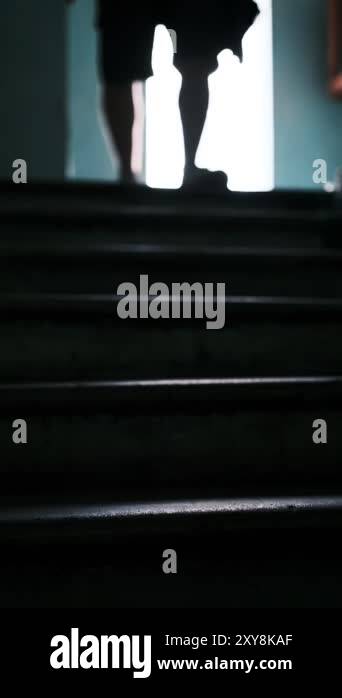 A man out of focus steps out from a brightly lit doorway descends dark ...