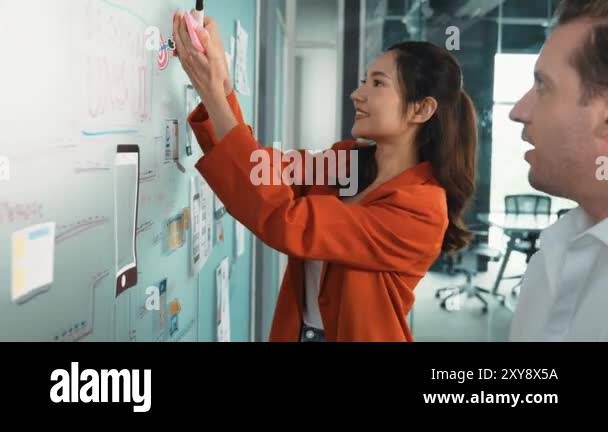 Portrait of group of businesspeople putting sticky notes on glass board ...