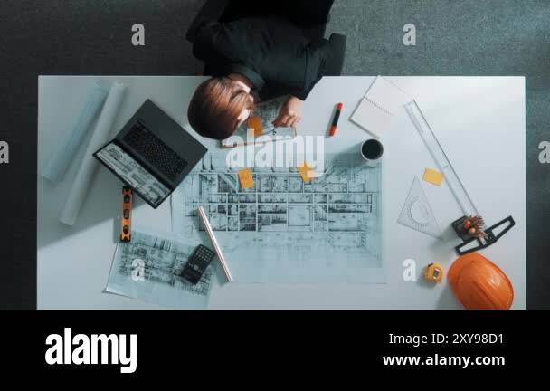 Aerial view of architect drawing while working at laptop. Top down view ...