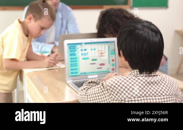 Energetic asian boy coding program and looking at camera in STEM class ...