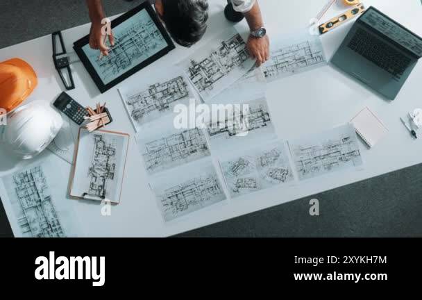 Top down view of engineer looking at tablet while using laptop to ...