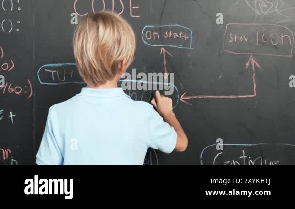 Back view of smart boy writing engineering prompt on blackboard while turn around and showing a ...