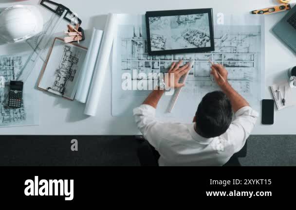 Top down view of relaxed architect engineer working on blueprint and ...