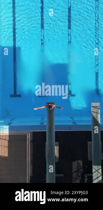 Drone footage capturing a diver mid-air performing a tuck dive above a ...
