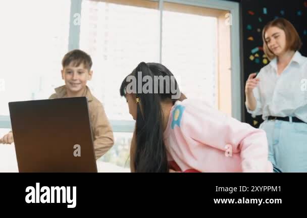 Young teacher looking at diverse student presentation in laptop and ...