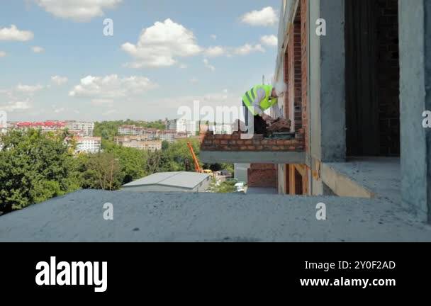 Construction worker placing bricks on an outdoor ledge. A construction ...