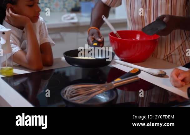 African American father man hand frying pancakes together with daughter ...