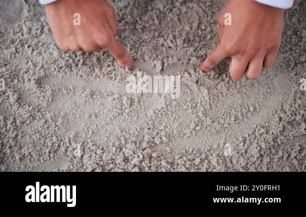 Two hands move in harmony, drawing a heart on the sand at the same time ...