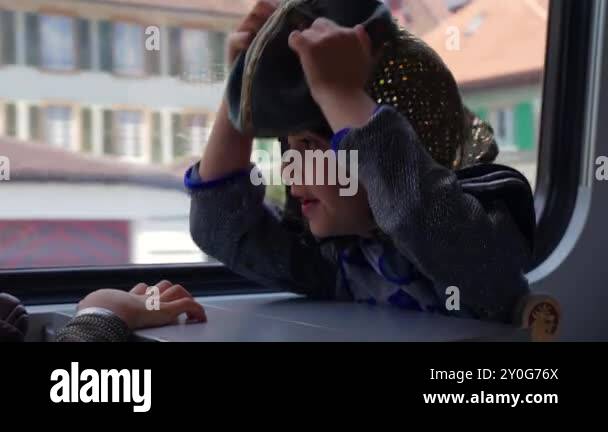 Young boy in knight costume carefully removing his helmet during train ...