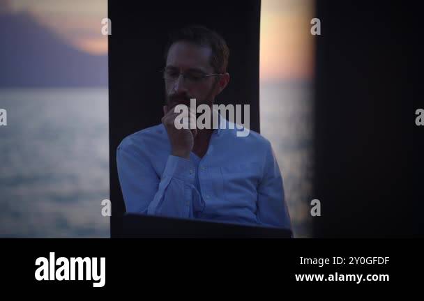 A deeply thoughtful man takes a moment to reflect while he sits against ...