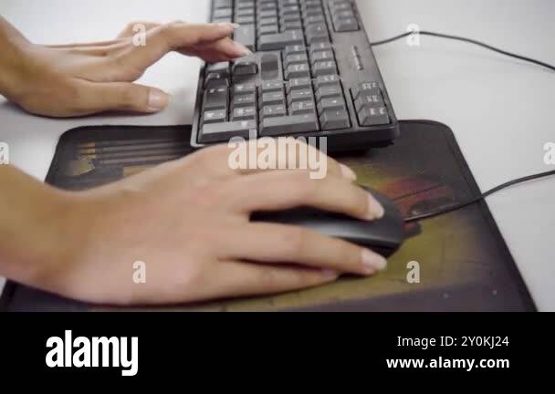Working on a computer hands typing and using mouse in office table ...