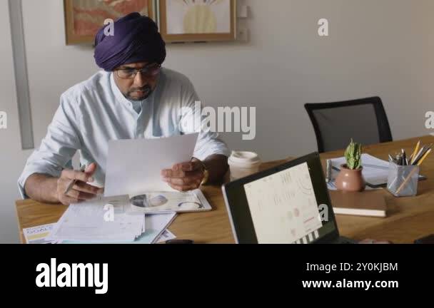 Zoom out view of Indian boss analysing financial report, then handing ...