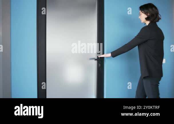 Female office worker in black suit opening a glass door. Professional ...