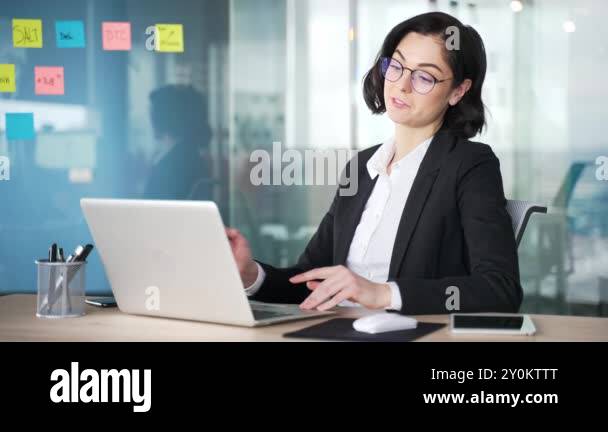 Female professional in business outfit at office desk engaged in a ...