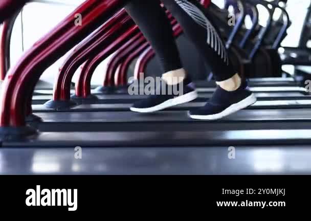 Treadmill in the gym. Side view of legs in sneakers running on the ...